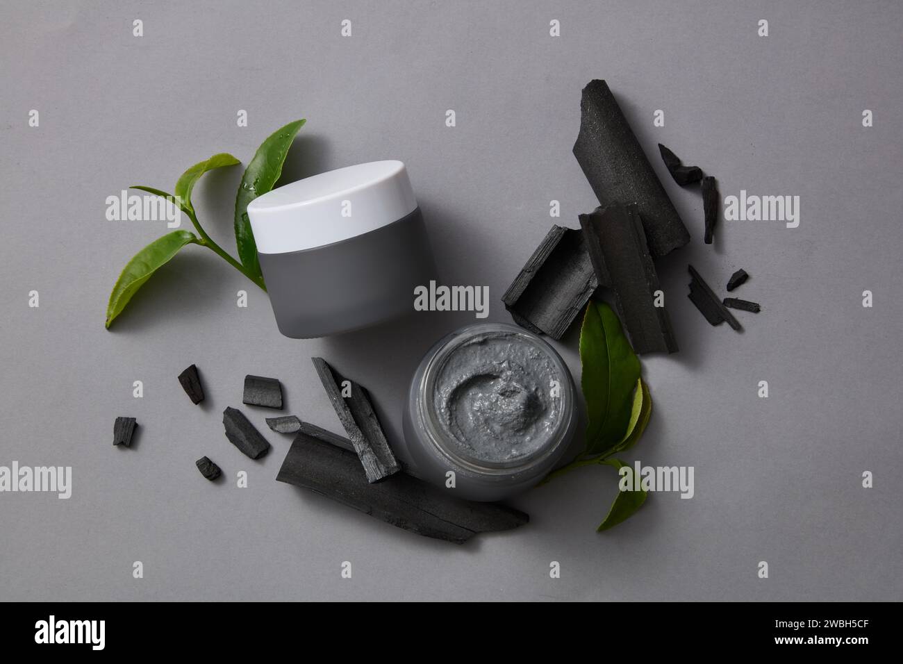 Over gray background, two unlabeled jars are arranged with fresh green ...