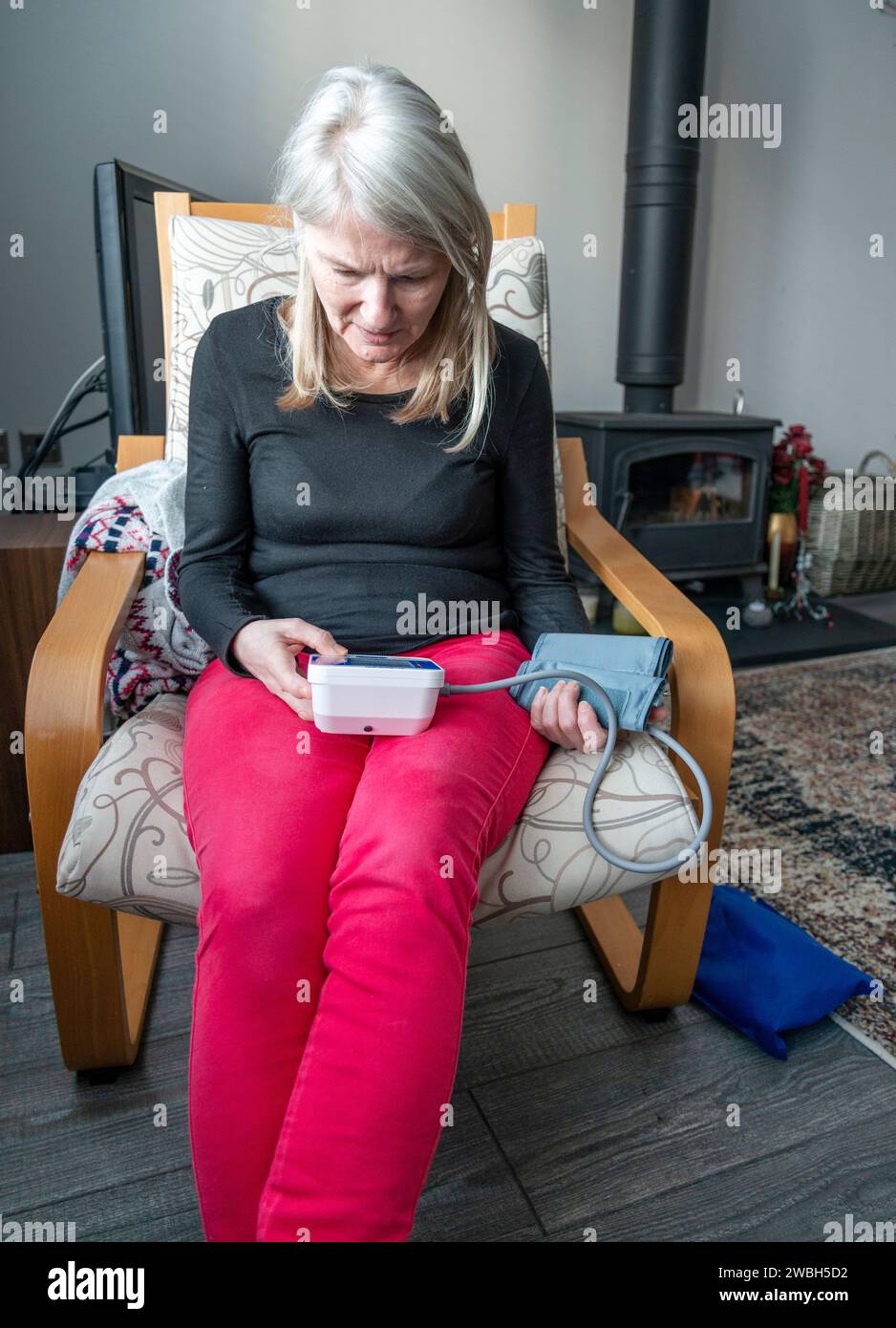 A health conscious female,sits in an armchair,in her house,using a ...