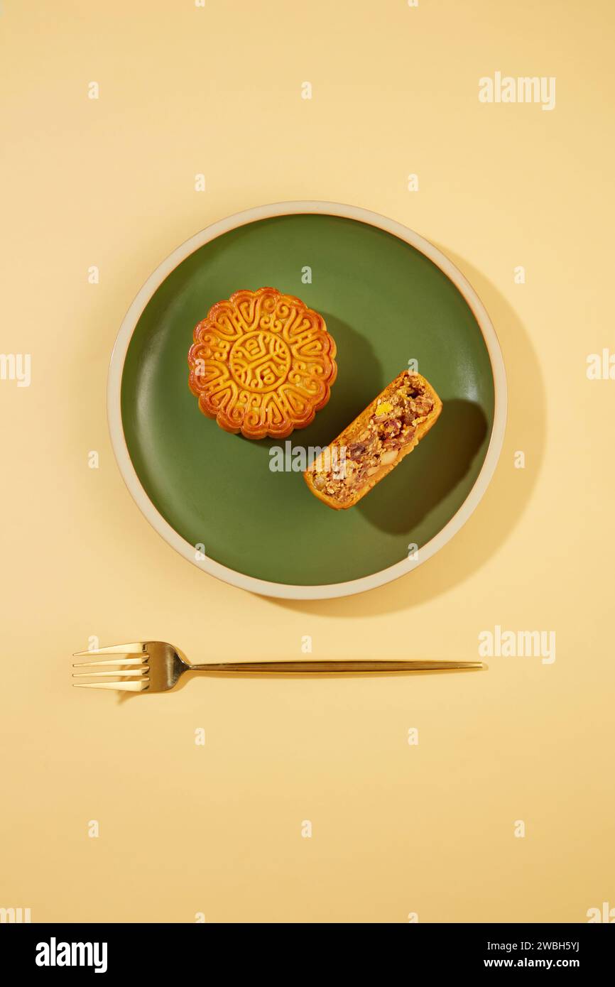 Against the pastel background, a green plate featured a mooncake and a ...