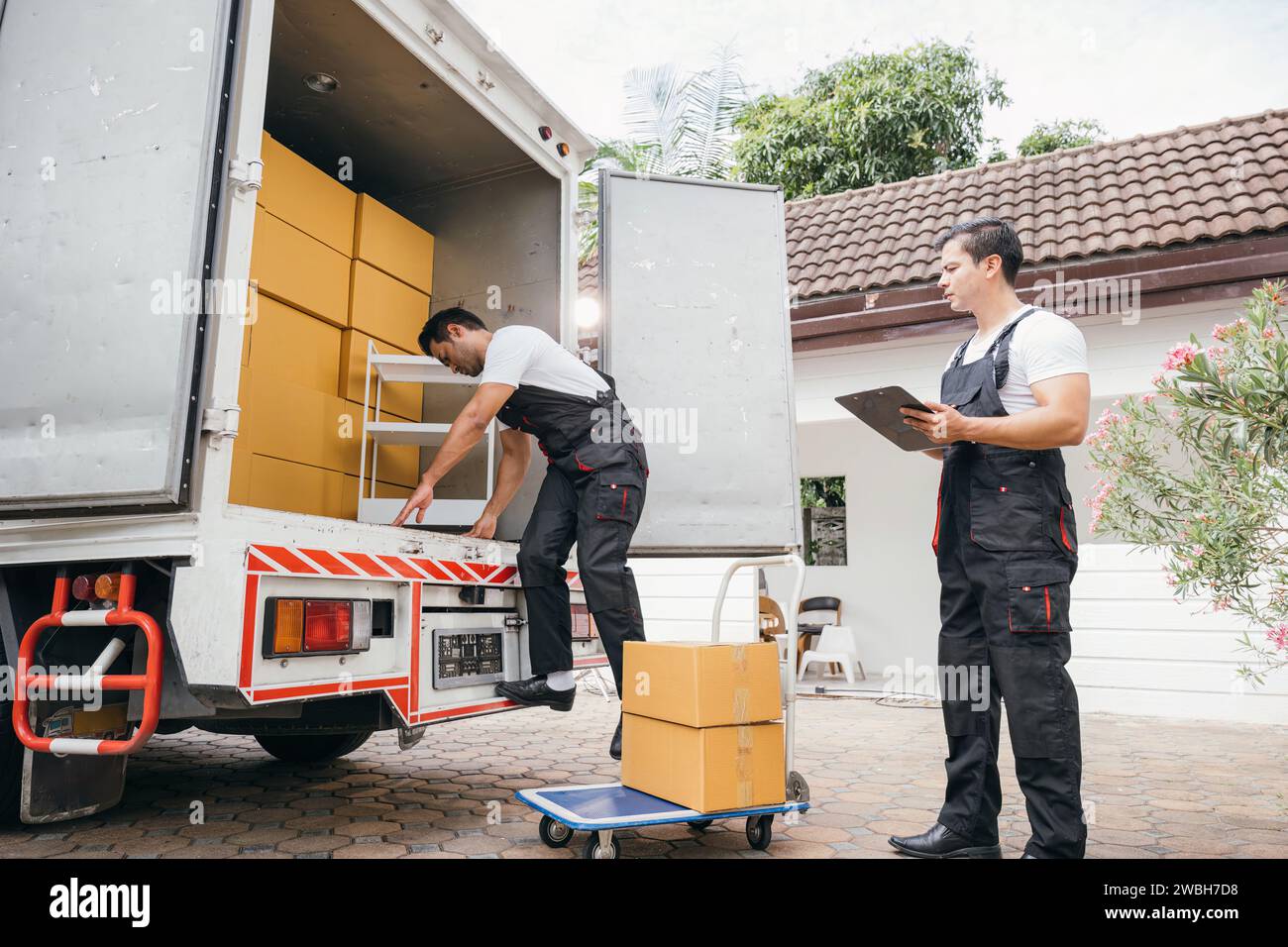 Uniformed removal company workers unload boxes and furniture from the ...