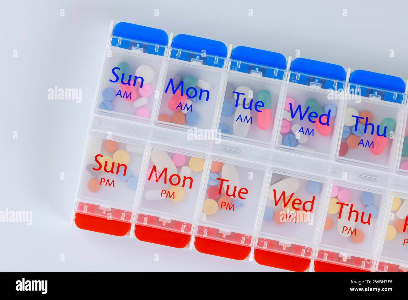 Organizer daily pill dispenser box with medications capsules on white ...