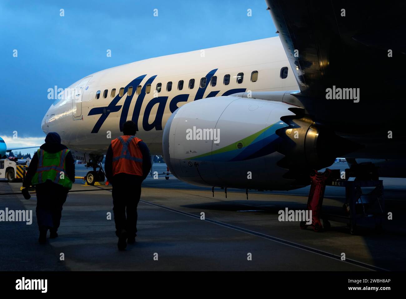 Workers walk by an Alaska Airlines Boeing 737 Max 9 aircraft with a ...