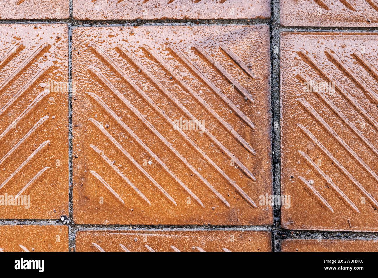 Shiny wet brown vintage floor tiling with anti-slip grooving, top view ...