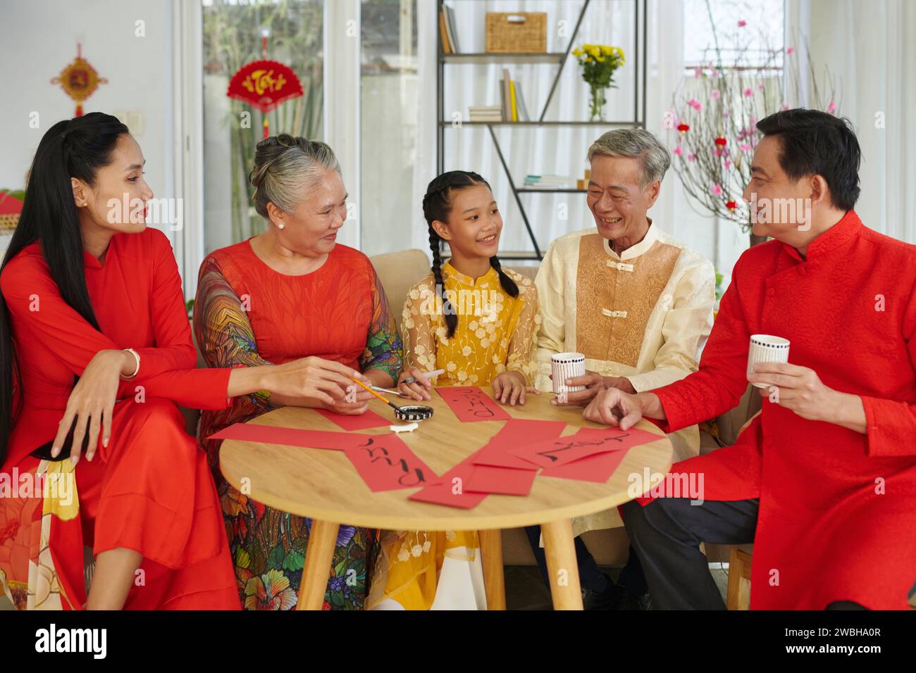 Happy big family practicing calligraphy together after Tet dinner Stock ...