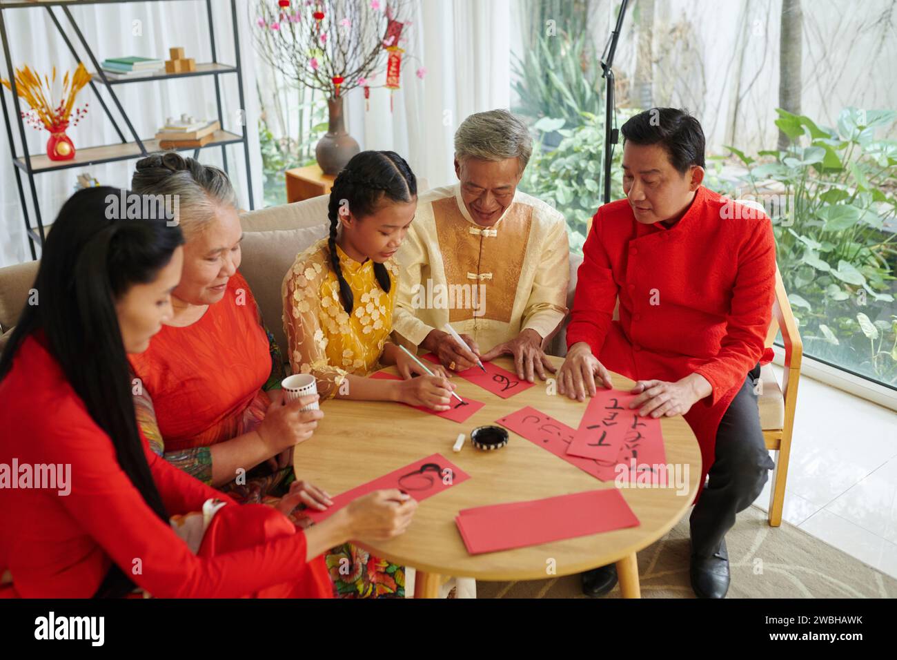 Teenage girl with parents and grandparents learning calligraphy Stock ...