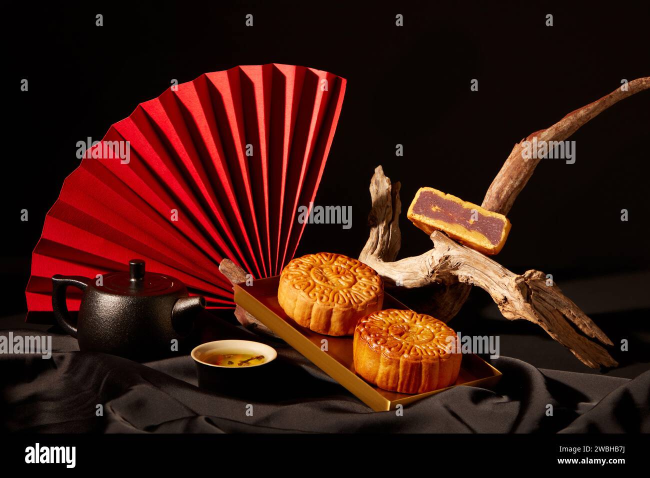 Tree branches, a golden dish of tasty mooncakes and a tea set arranged ...