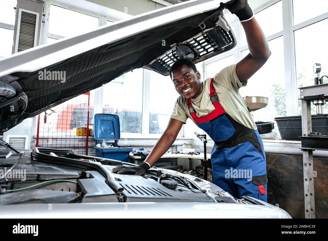 Young African man working under the hood of car fixing engine in auto ...