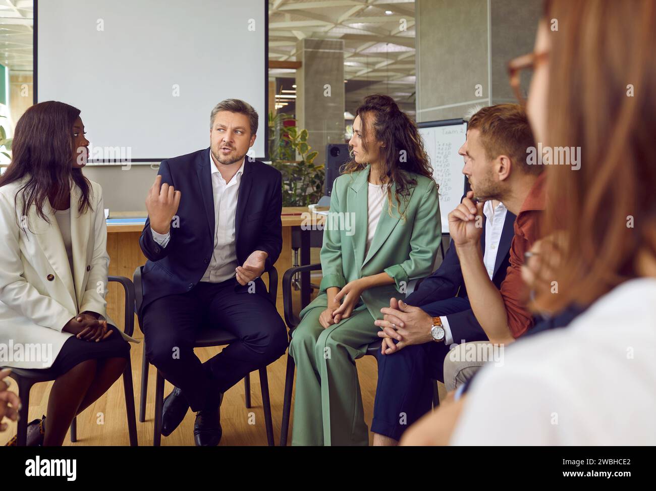 Team of people listening to business mentor talking about success and ...