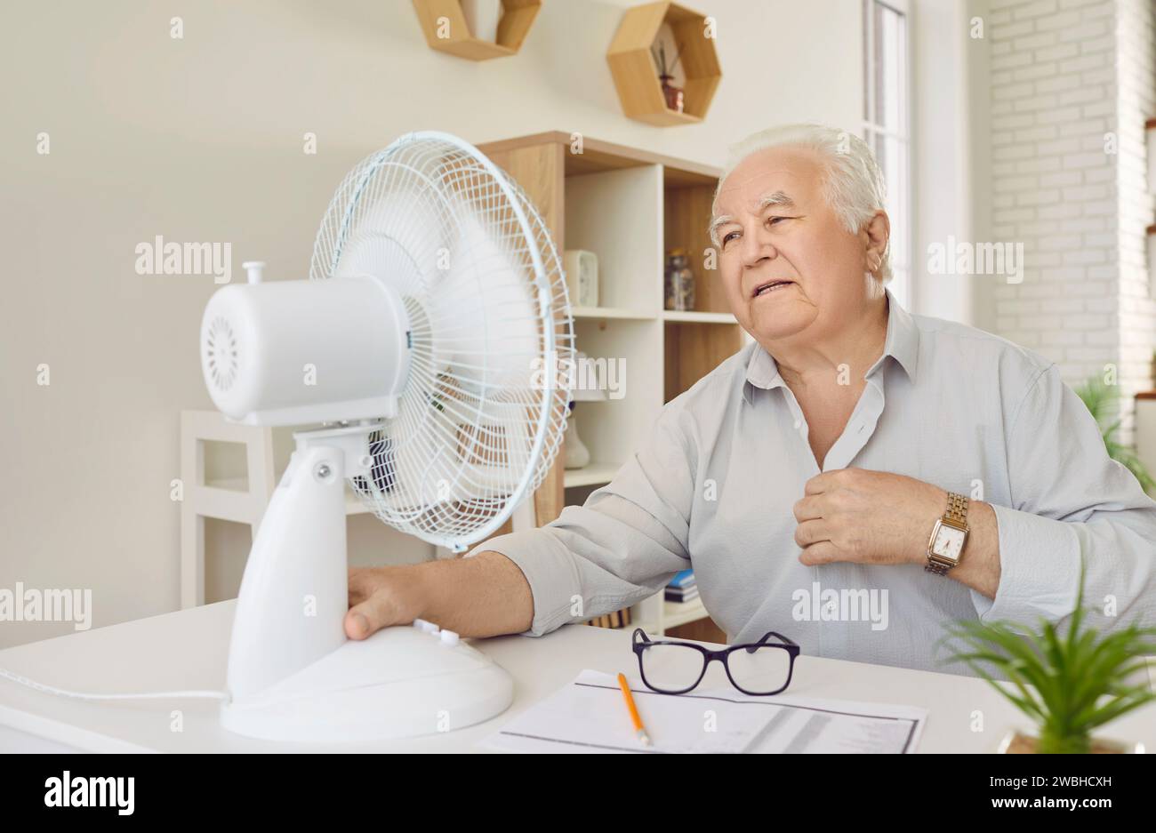 Tired upset senior retired person using electric fan during heatwave ...