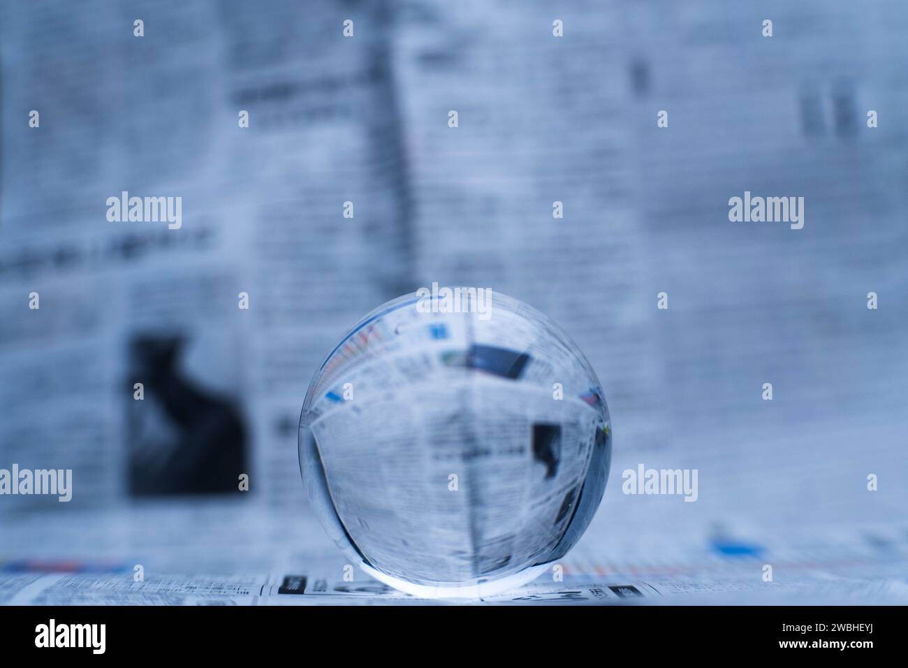 A glass globe reveals the letters inside, with a newspaper in the ...