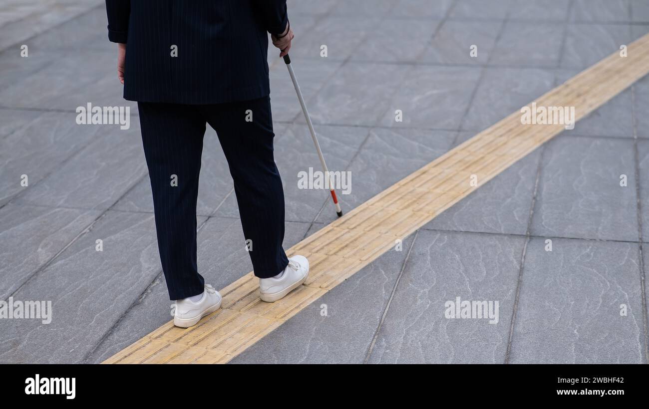 Close-up of the legs of a blind businesswoman walking along a tactile ...