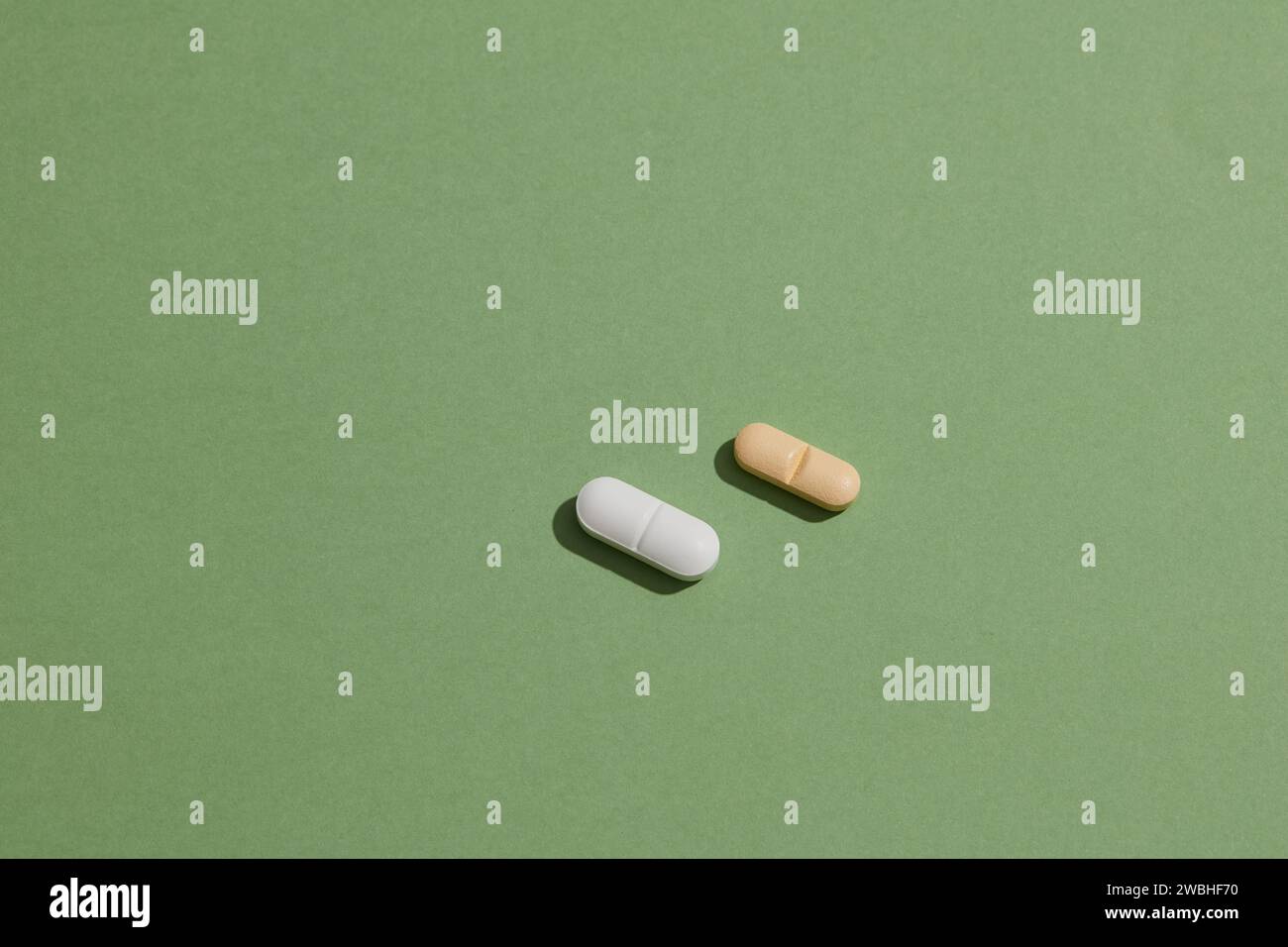Pharmacy theme, white and beige medicine tablets on a green background ...