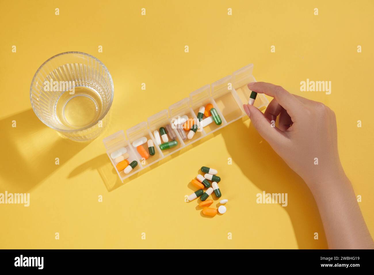 Top view of drug container with pills, female hand is holding a capsule ...