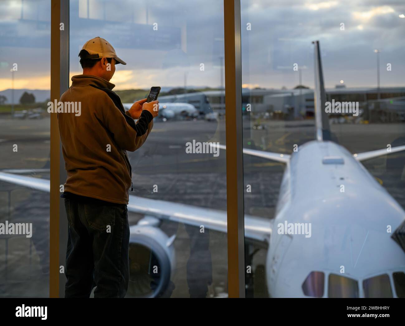 Man taking photos using smartphone of an aeroplane at the airport ...