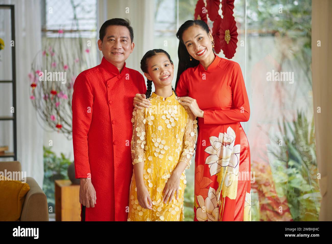 Smiling parents and their teenage daughter wearing traditional costumes ...