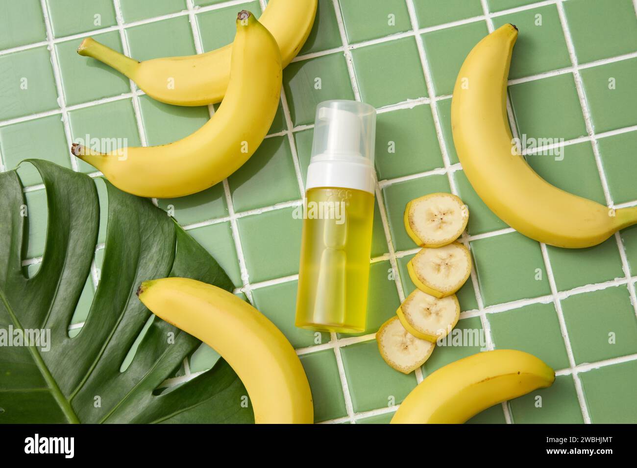 Unbranded transparent bottle of yellow liquid placed on green mosaic ...