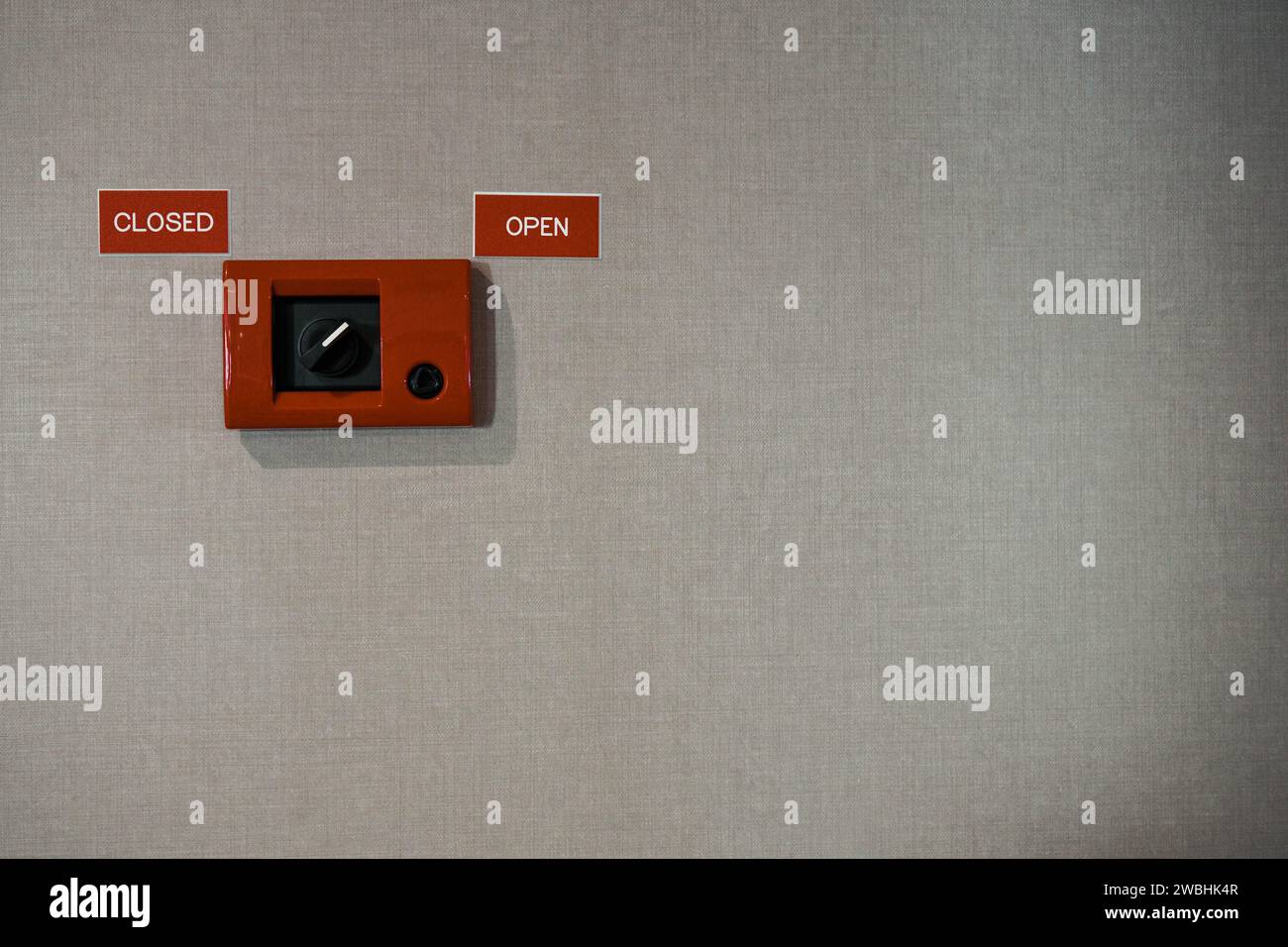 Close-up view of a red switch box mounted on a textured grey wall. The ...