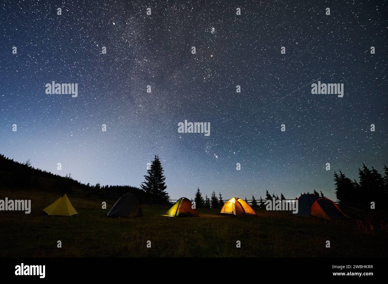 Night camping in mountains under starry sky. Tourist tents in campsite under beautiful sky full ...