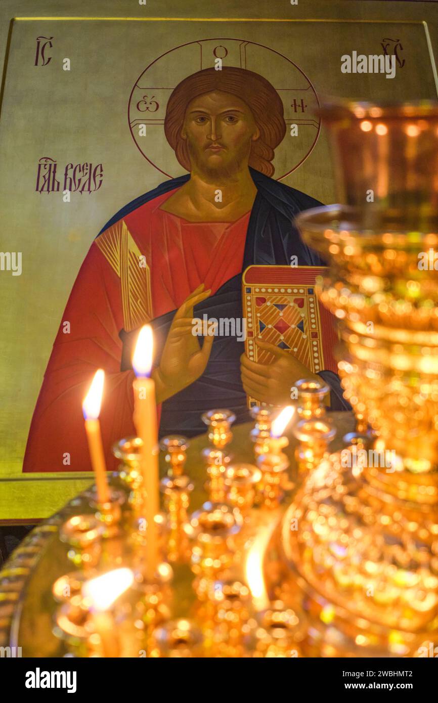 An icon painting of Jesus Christ, behind the glow of memorial candles ...