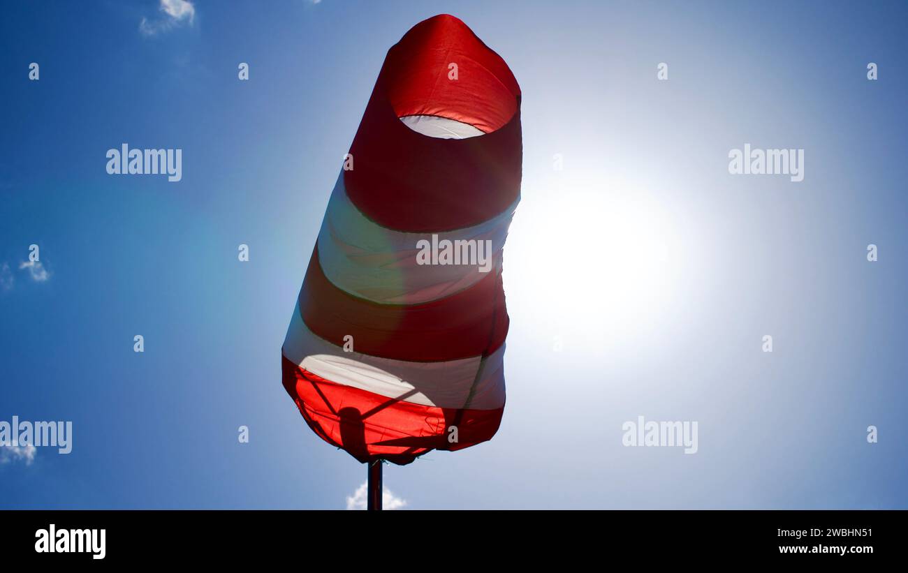 Windsock in front of blue sky. Indicator filled with wind in front of ...