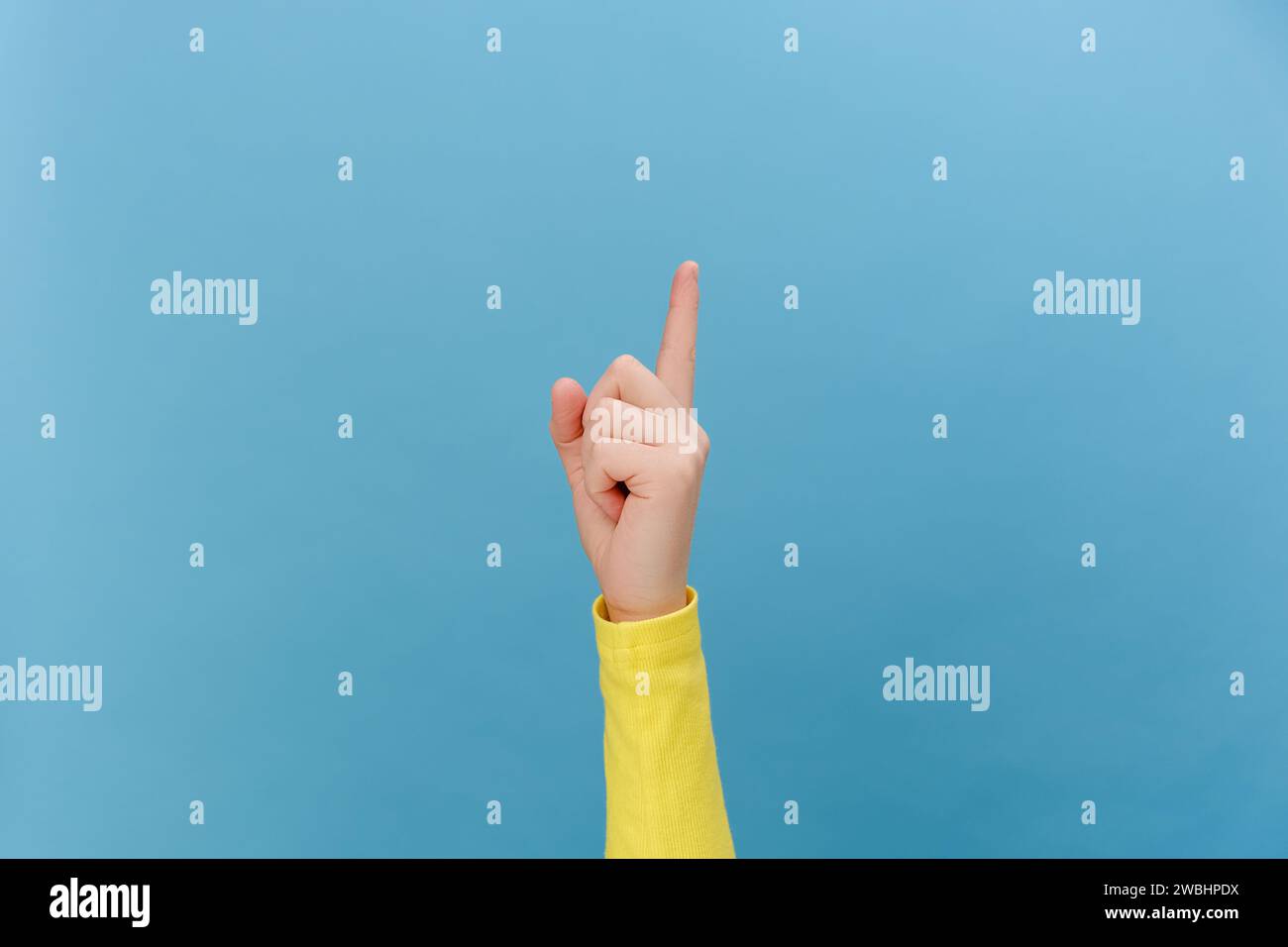 Close up of female hand pointing up demonstrating blank area on blue ...