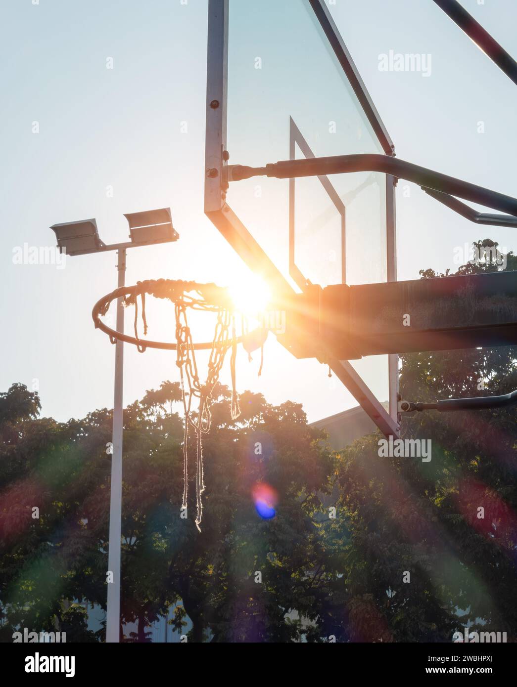 basketball hoop and board against the sun with beautiful sun flare in ...