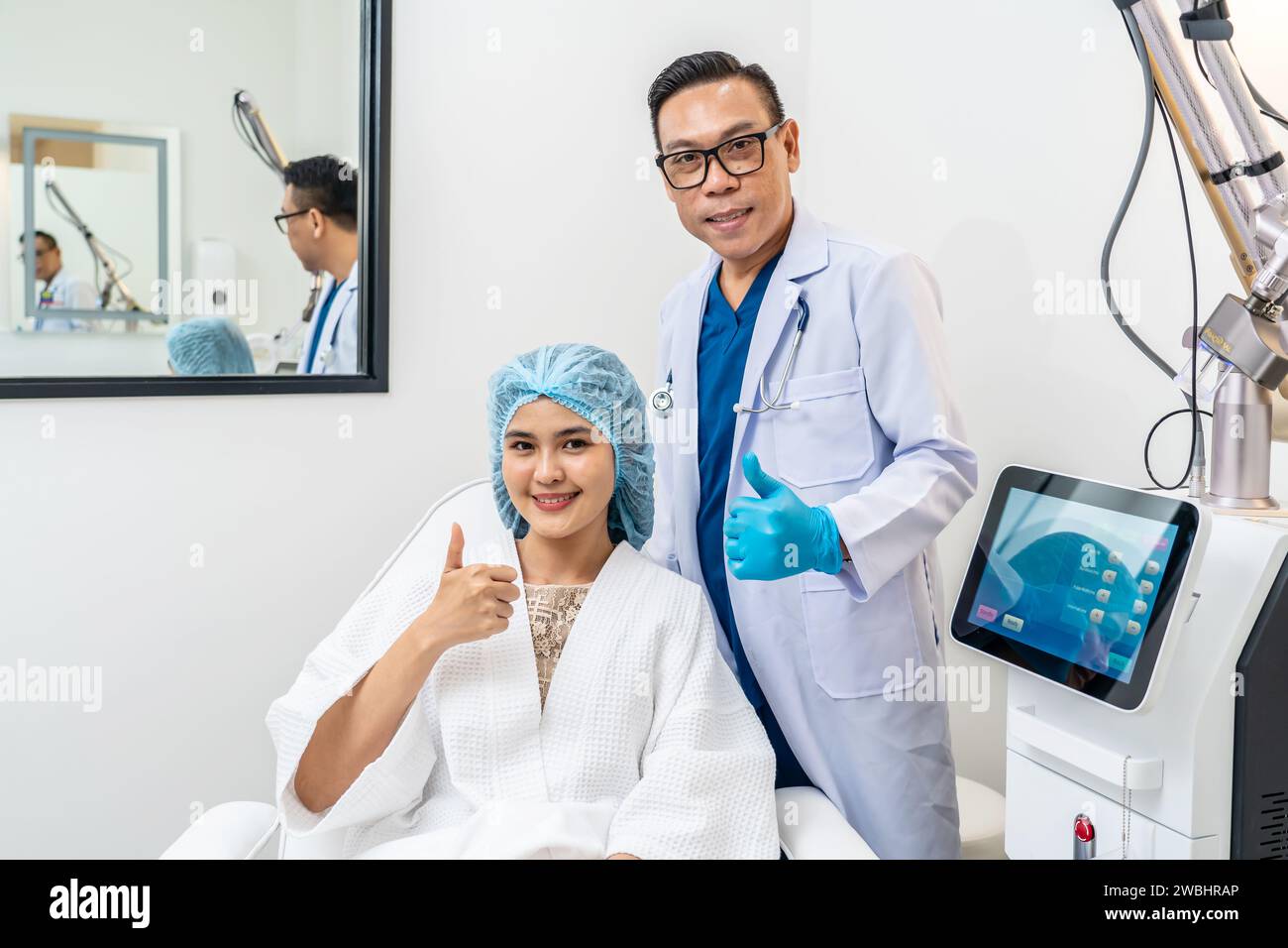 Asian male cosmetologist and young woman patient with blue cap on head ...