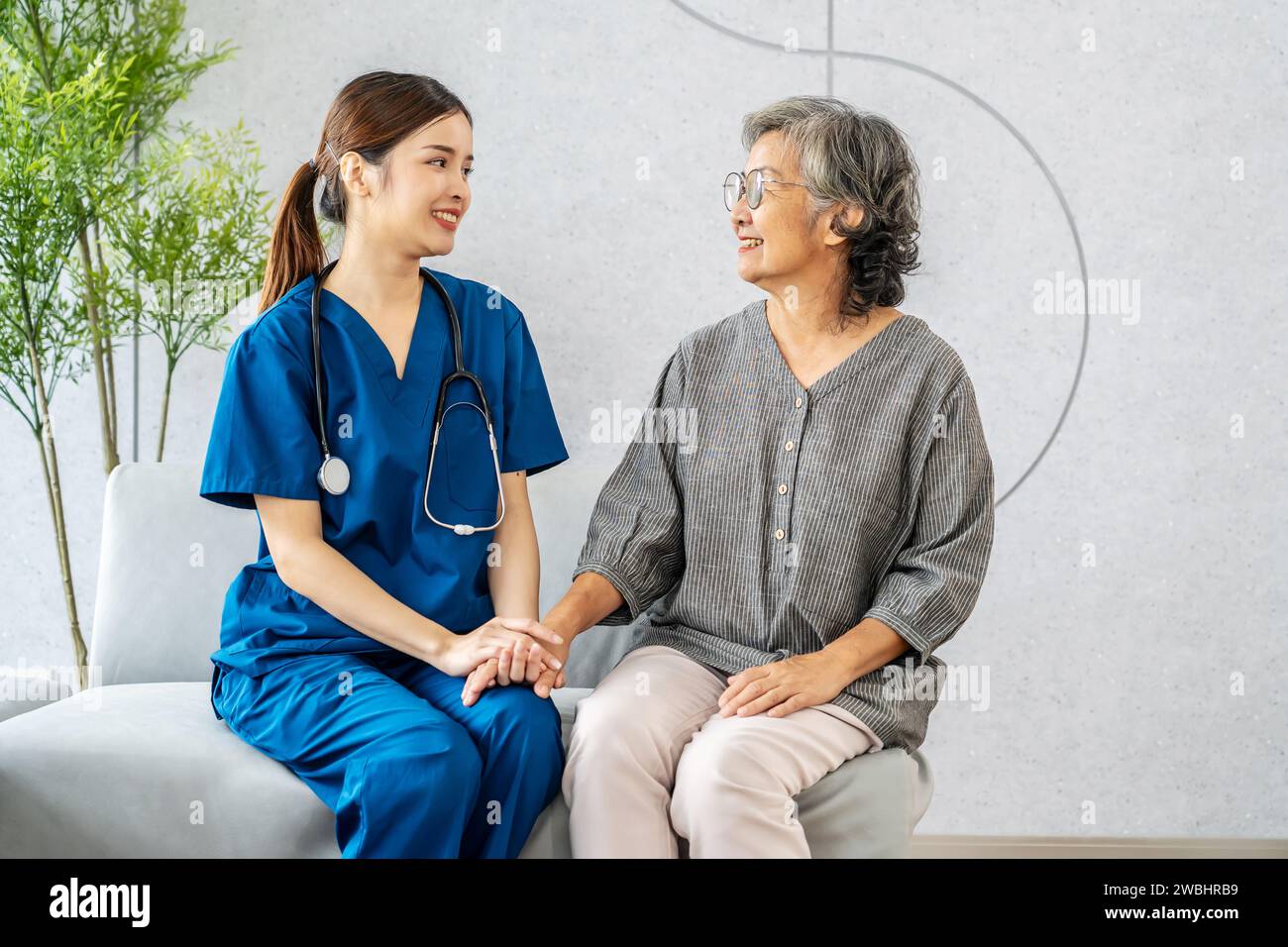 Young asian female doctor or nurse happily supports elderly patient ...