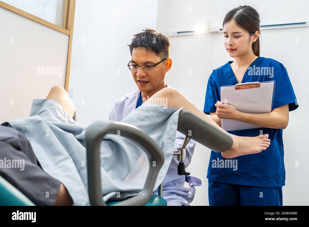 Male asian doctor doing internal examination on female patient at ...