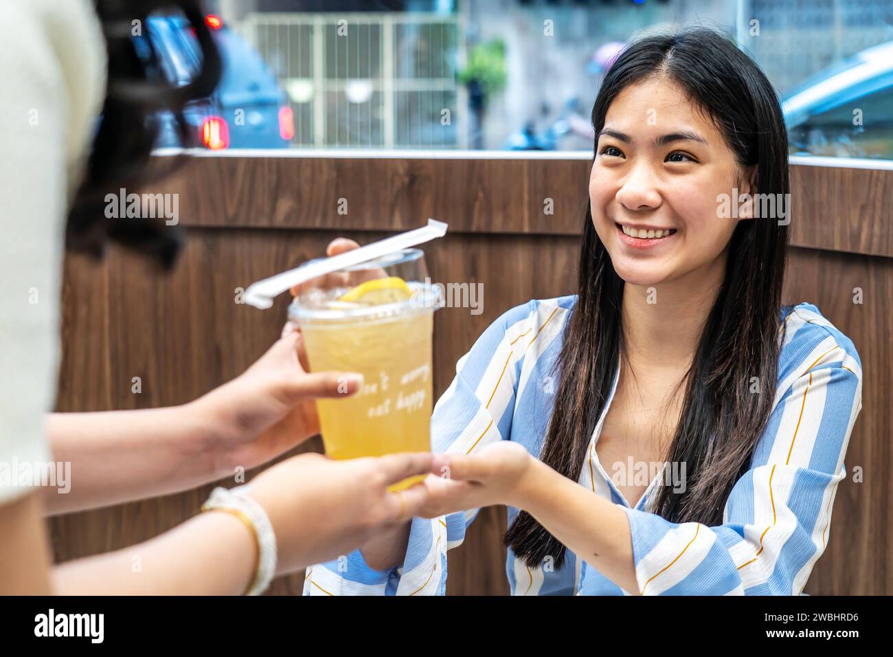 Waiter serving glass of fresh juice to customer who was a young asian ...