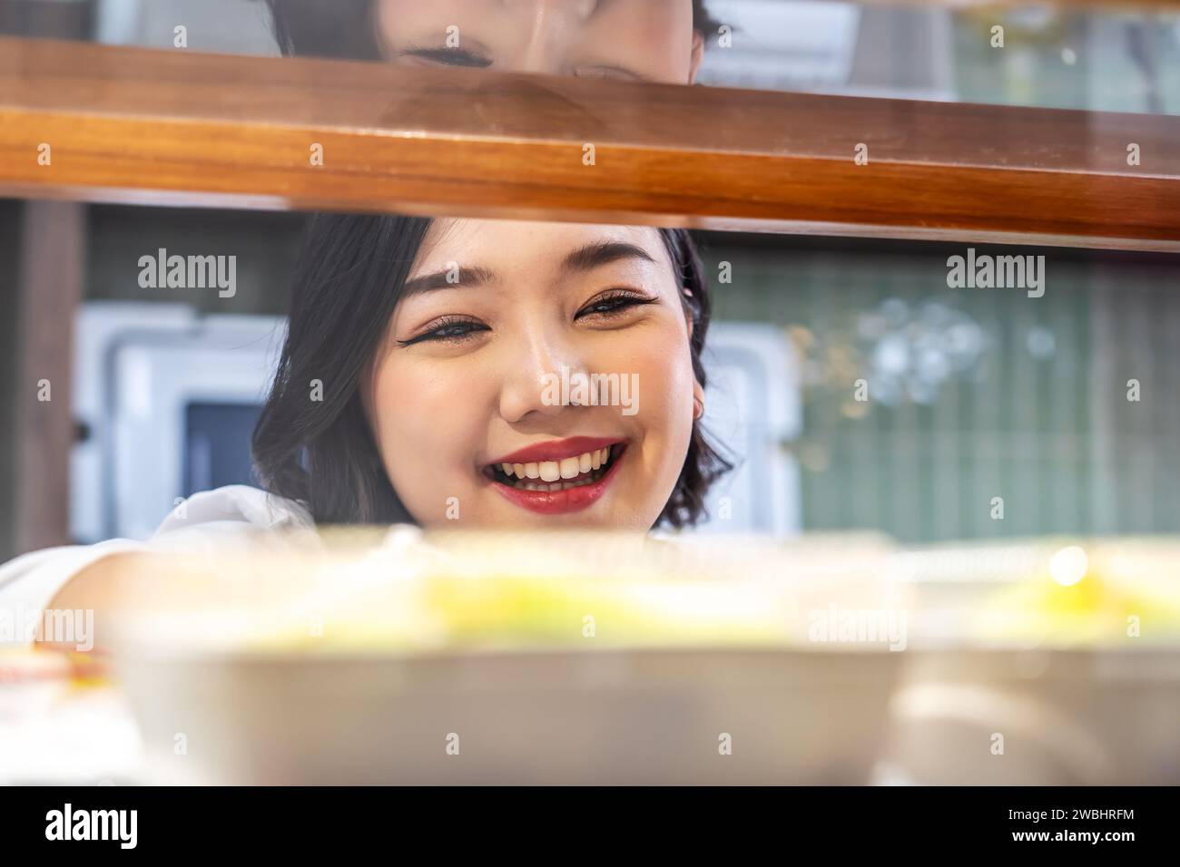 Beautiful female young asian worker standing by shelf and arranging ...