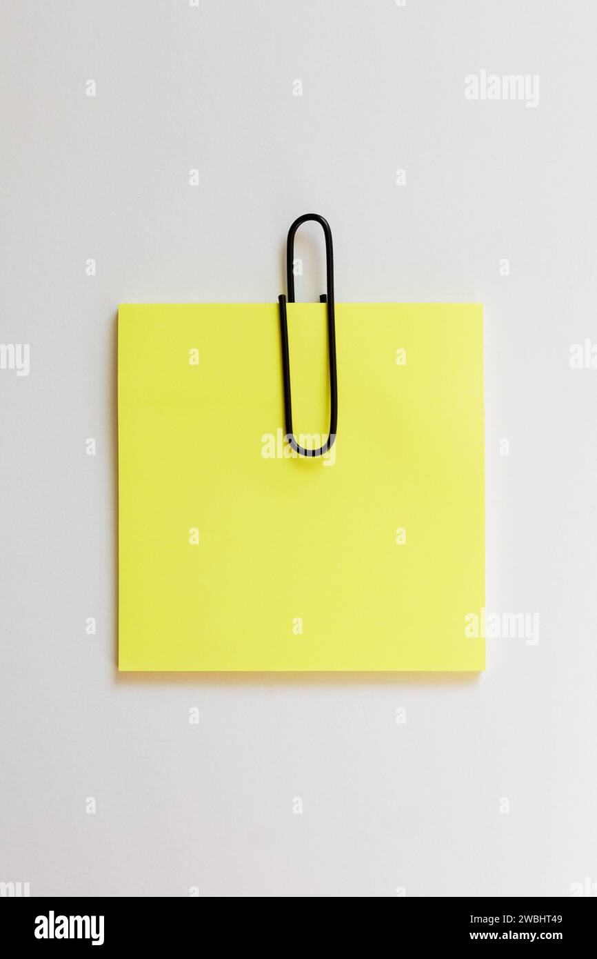 yellow sticky note with paperclip over white background Stock Photo - Alamy