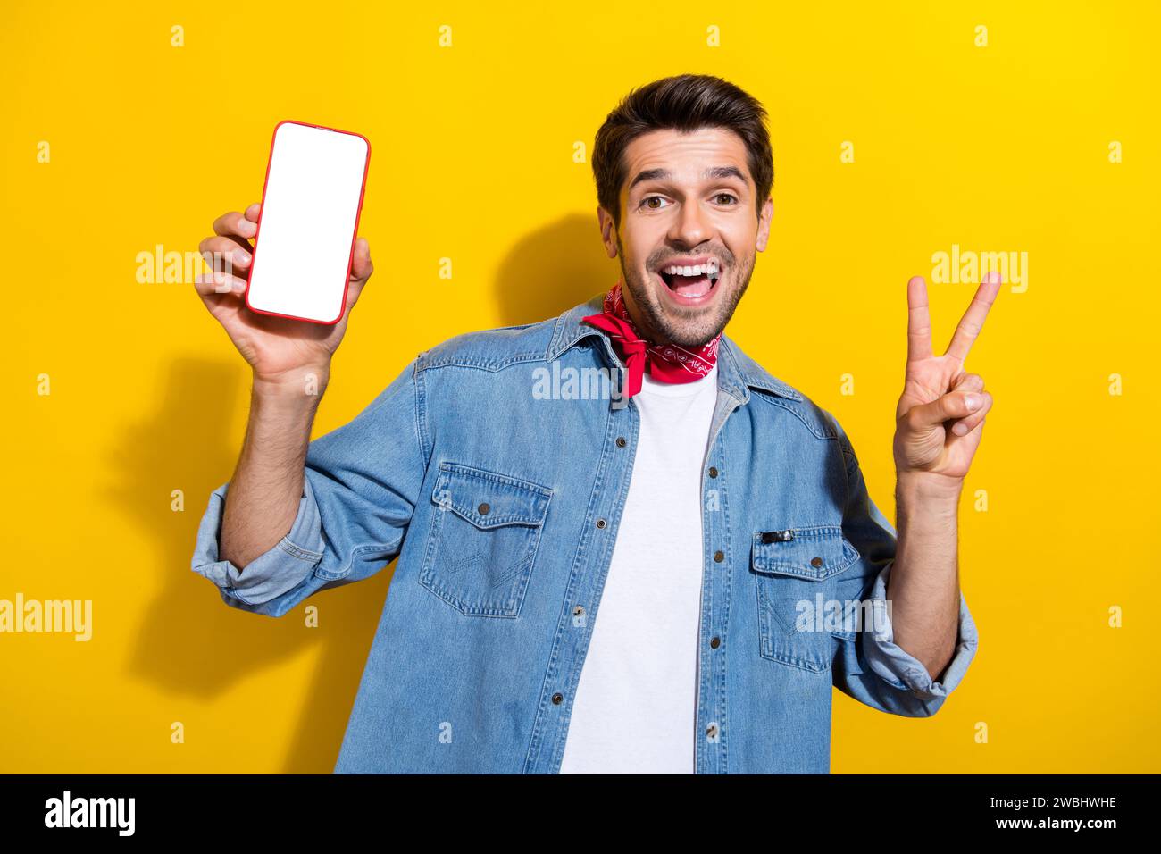 Photo portrait of handsome young guy hold telephone show v-sign dressed ...