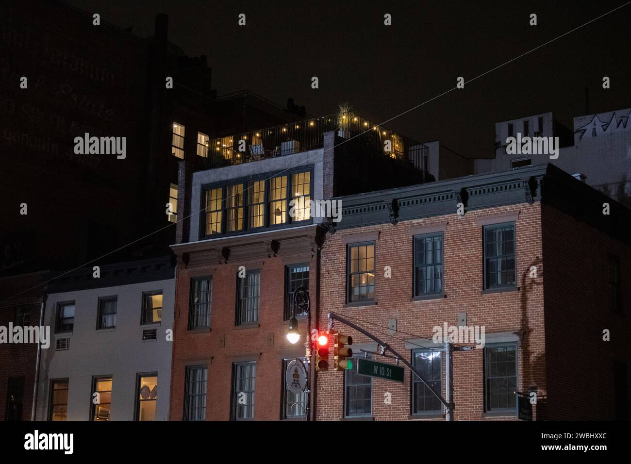 A brightly lit building on the other side of a bustling city street ...