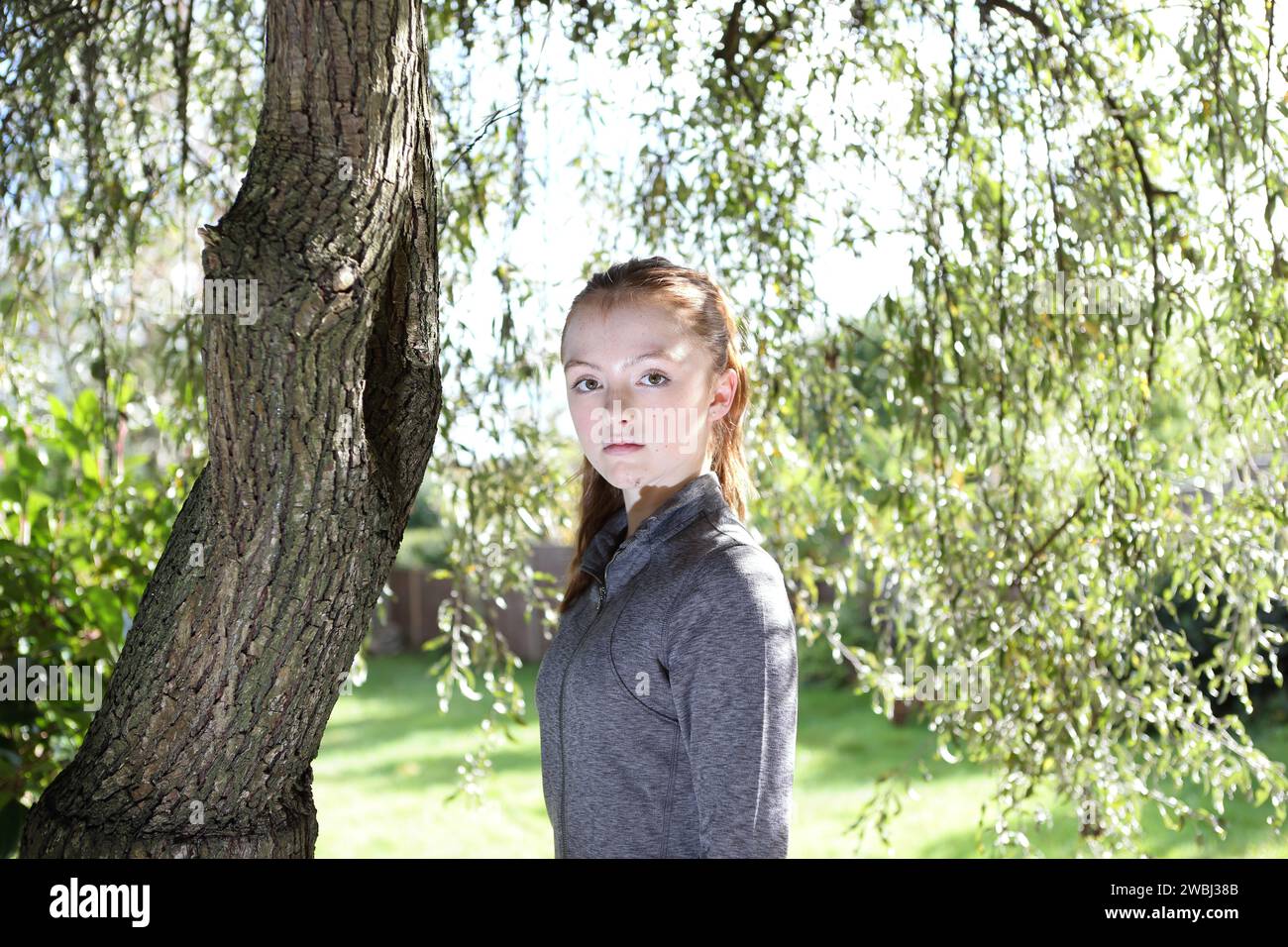 Portrait of teenage girl staring making strong eye contact wearing grey ...