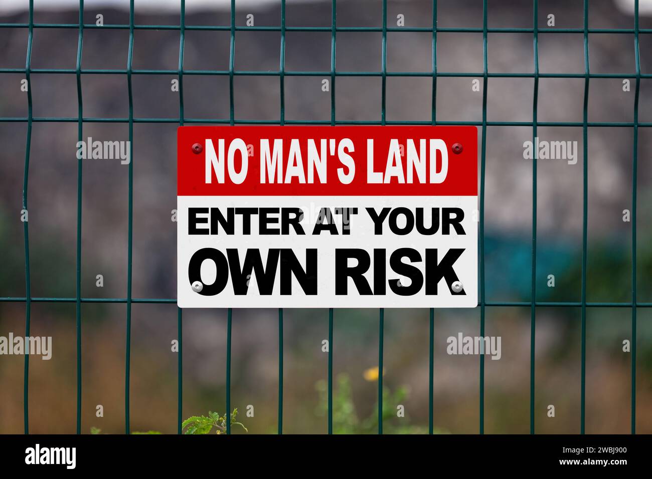 Red an white warning sign on a fence stating in "No man's land - Enter ...