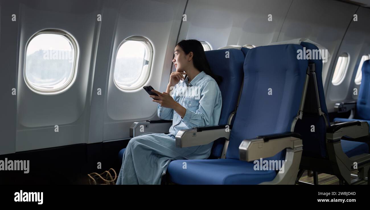 Asian people female person onboard, airplane window, using mobile while ...