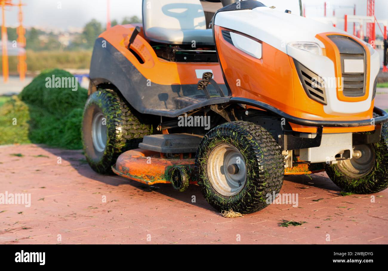 Tractor lawn mower close-up on the background of a heap of mown grass ...