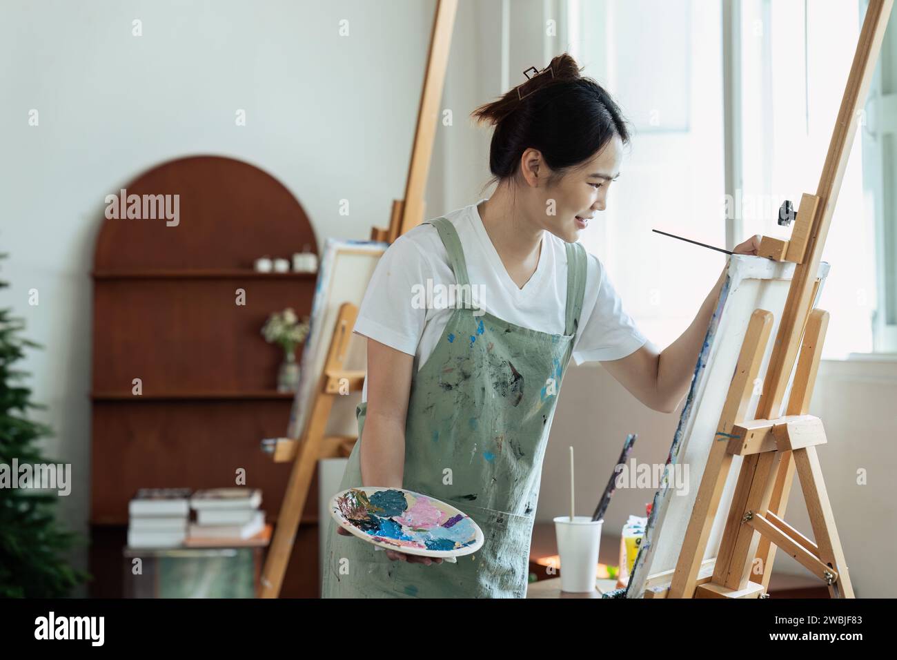Female artist hold color palette and paintbrush for painting during ...