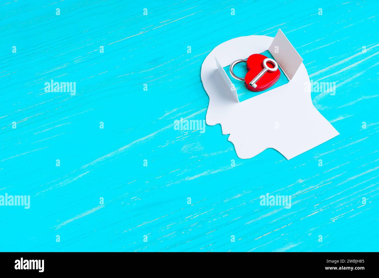 Paper-cut human head with an open window, revealing a red heart-shaped ...