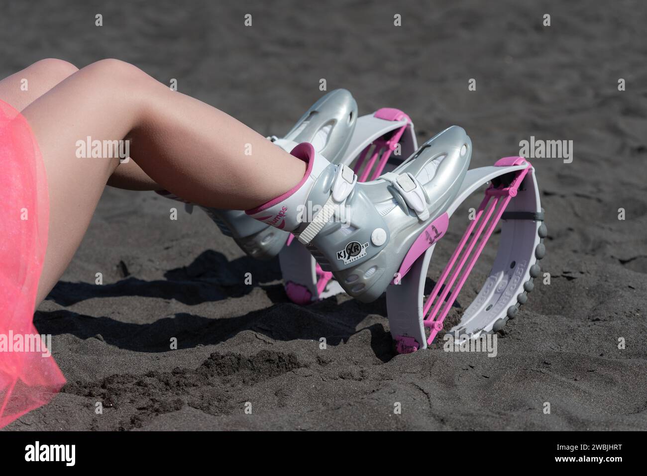 Closeup slim female legs in sports Kangoo Jumps boots, short pink skirt ...