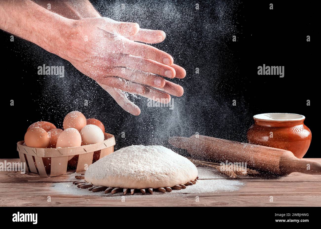 The baker claps his hands with flour over the dough. A man is preparing ...