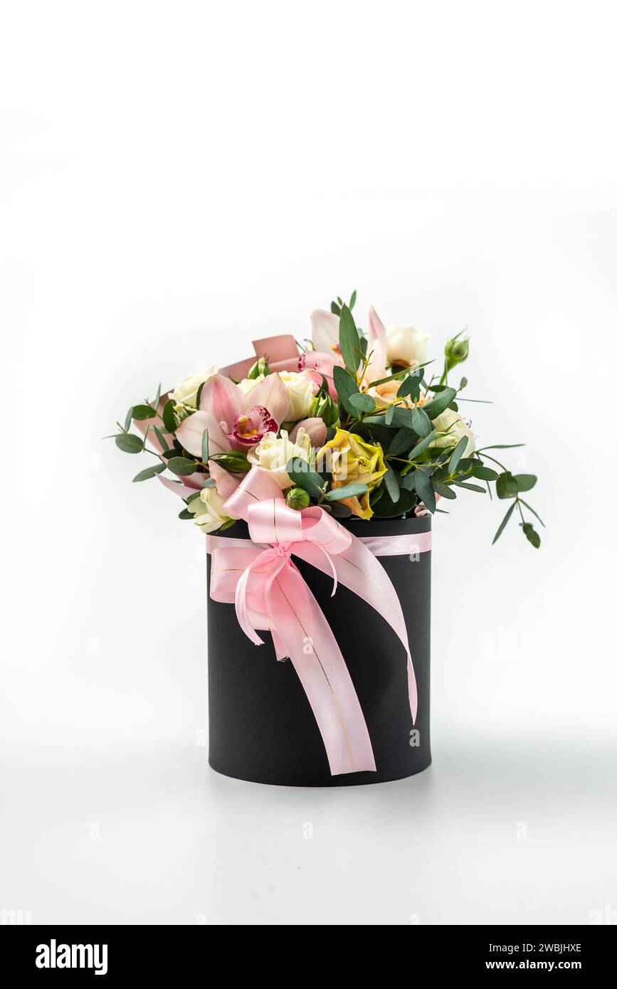 Flower arrangement in a hat box, a pot of roses and orchids on a white ...