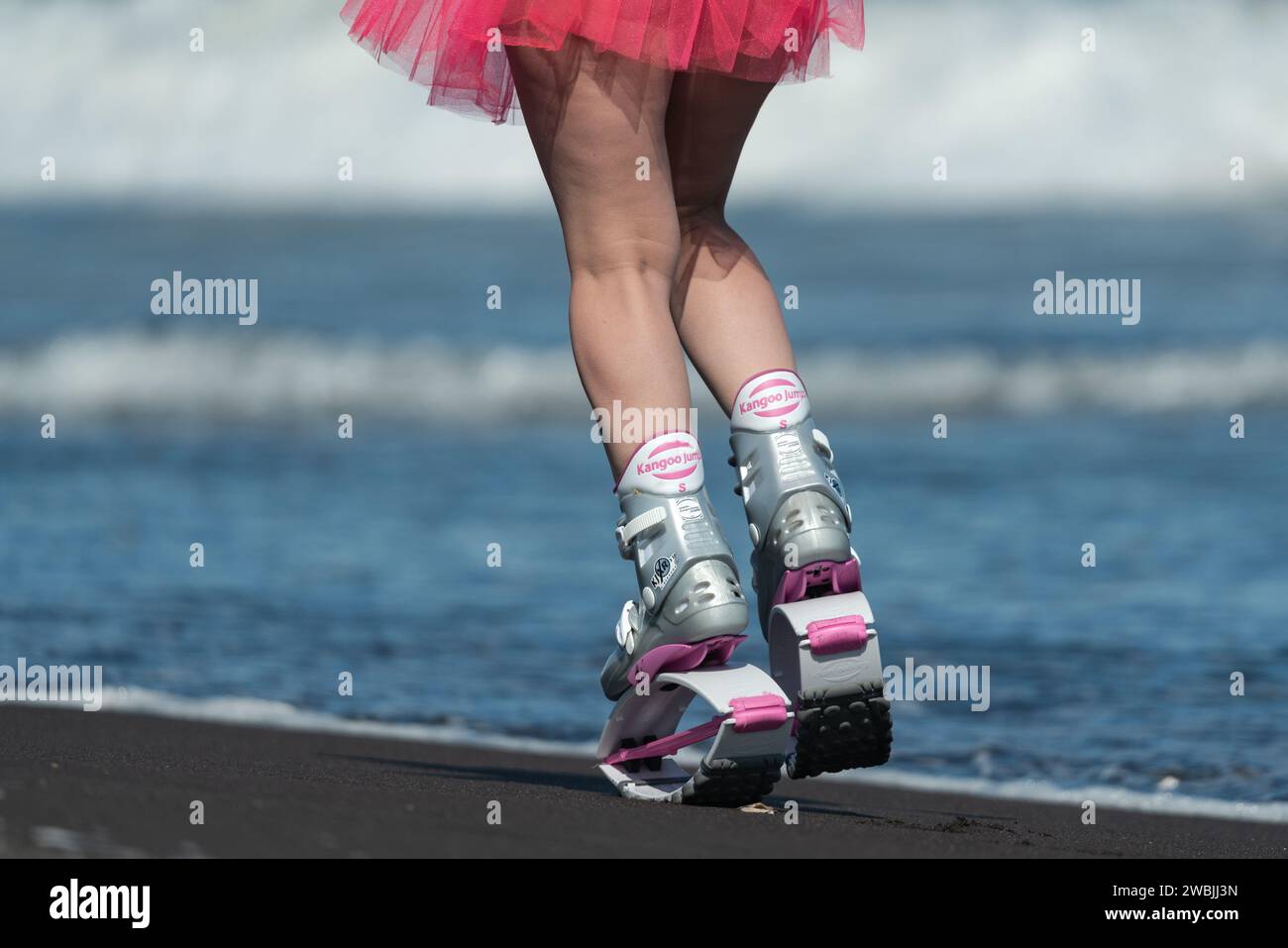 Rear cropped view of sportive woman legs in sports boots Kangoo Jumps ...