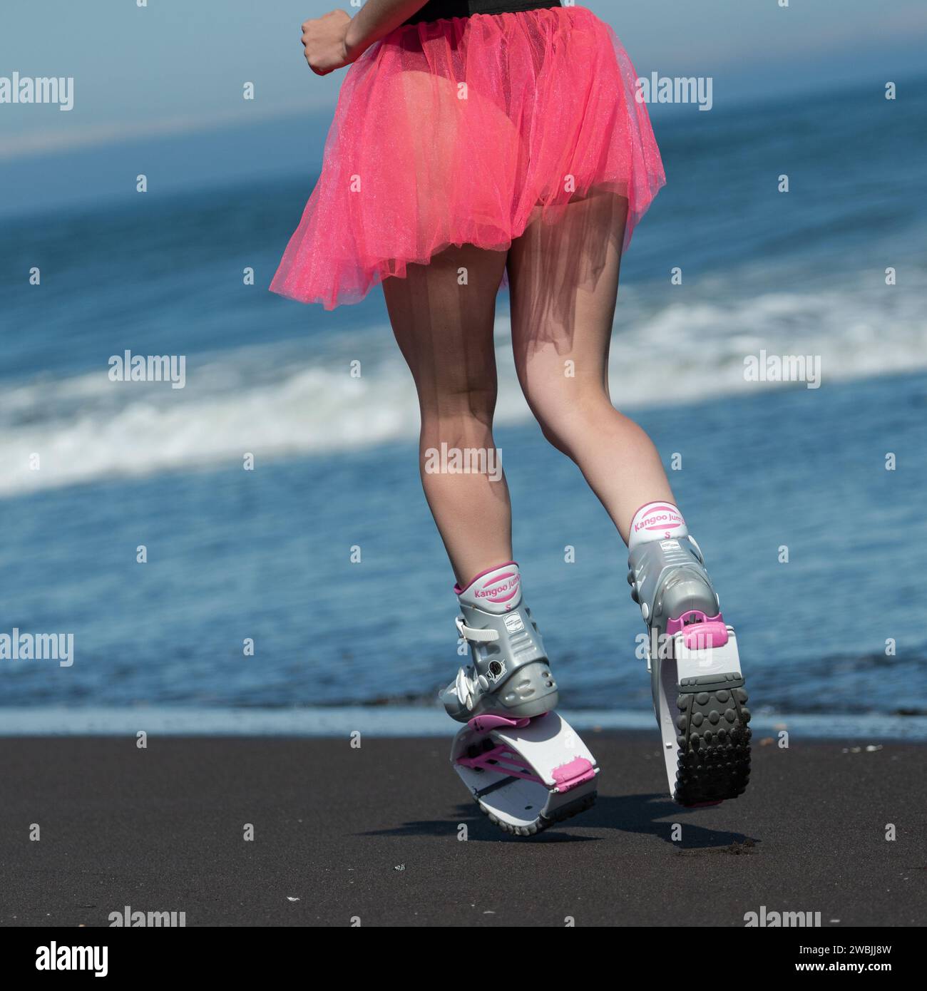 Rear view of female legs in sports Kangoo Jumps boots, swimsuit and ...