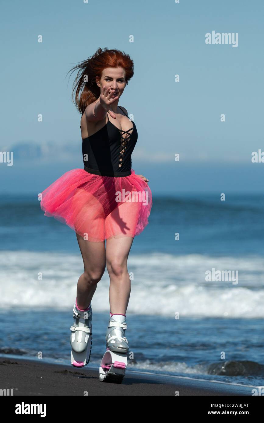 Fit woman in sports Kangoo Jumps boots, black one-piece swimsuit and ...