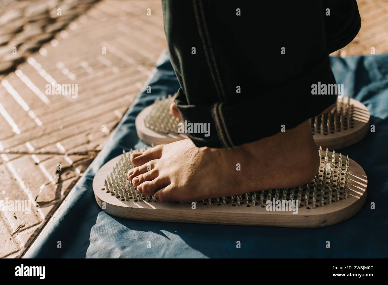 Feet standing on a Sadhu board (Yoga board) with sharp nails outdoor ...