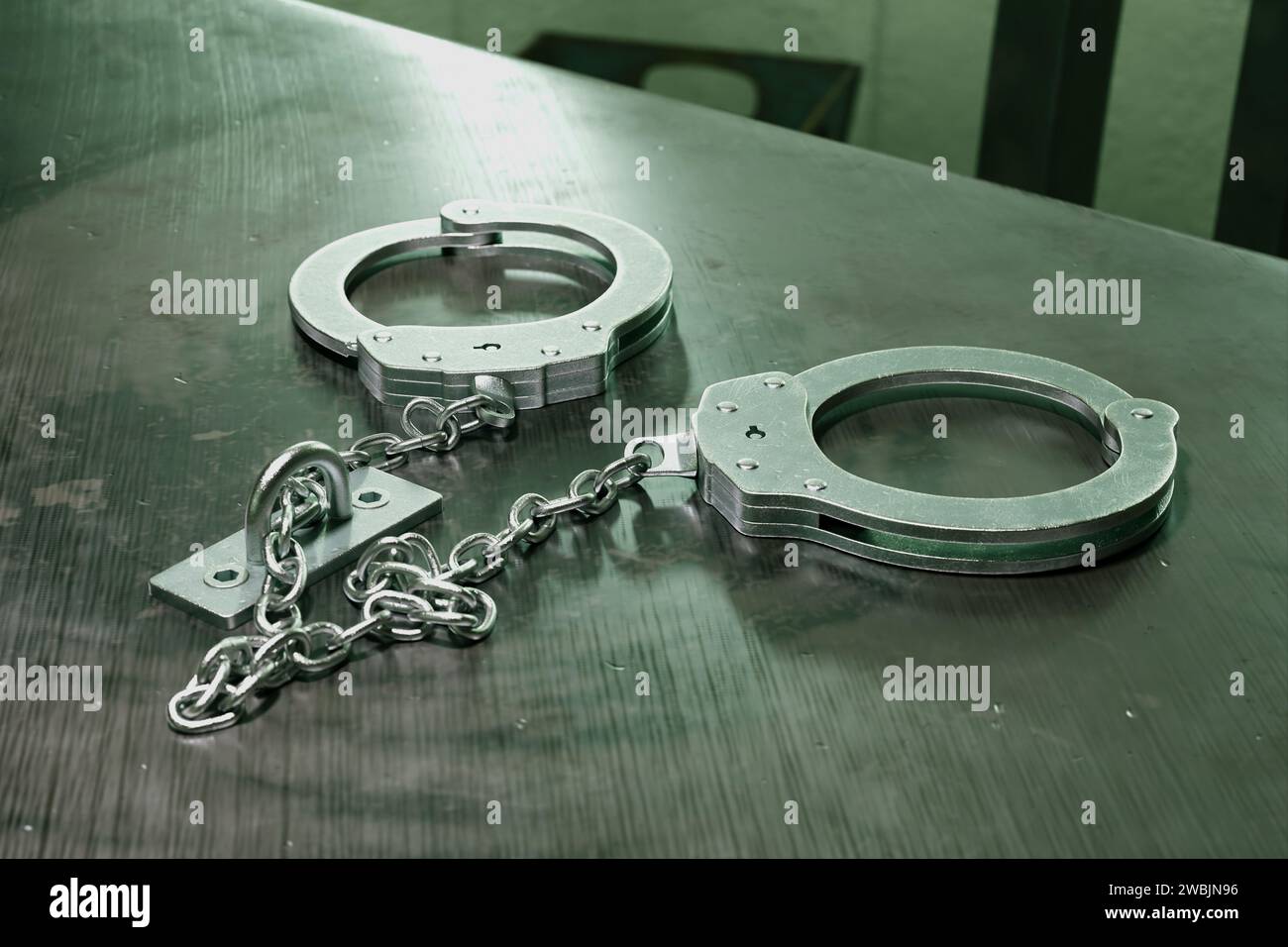 An image of open chrome handcuffs placed elegantly on a dark green ...