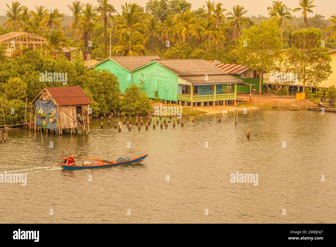 long tail boat passes riverside houses during the dry season, Southern ...