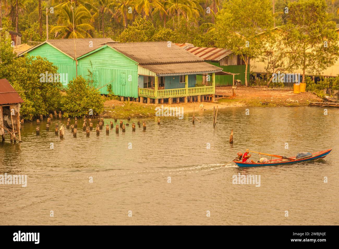 long tail boat passes riverside houses during the dry season, Southern ...